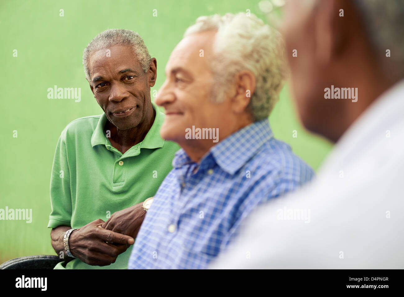 three senior men sitting on bench in park and talking Stock Photo - Alamy