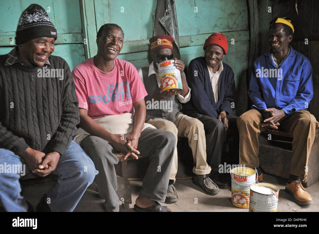 A group of men drink home-brewed beer in a poverish shanty in a ...