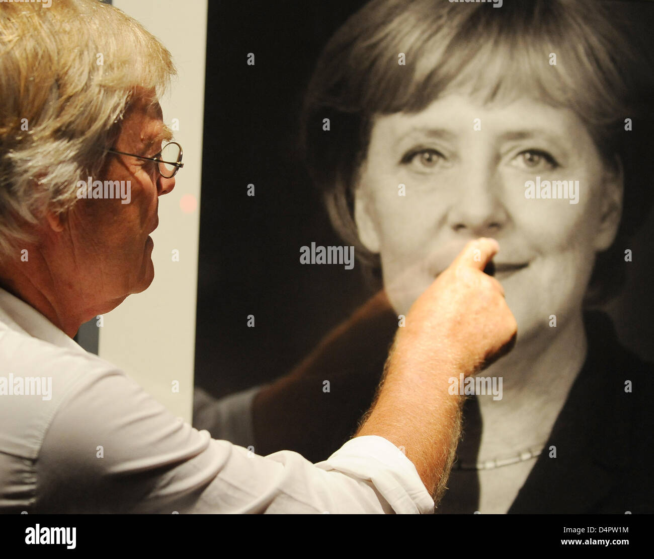 Photographer Rufus Mueller points at one of his portrait photos of ...