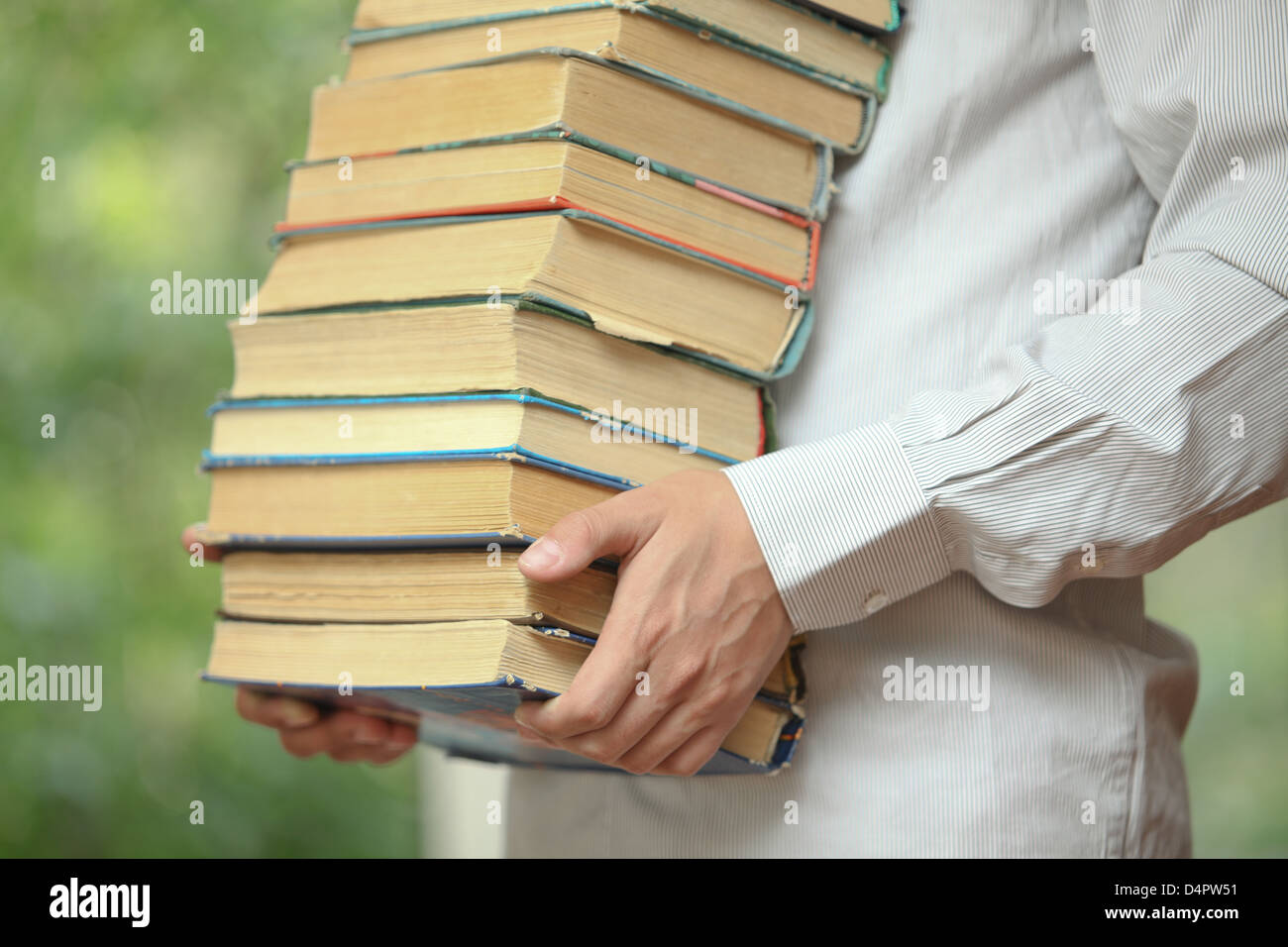 Guy in a shirt holding a stack of old books Stock Photo - Alamy