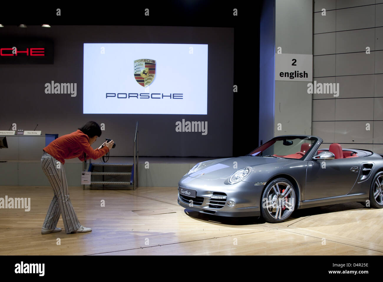 A woman takes a picture of the new Porsche Turbo at the Porsche stand ...