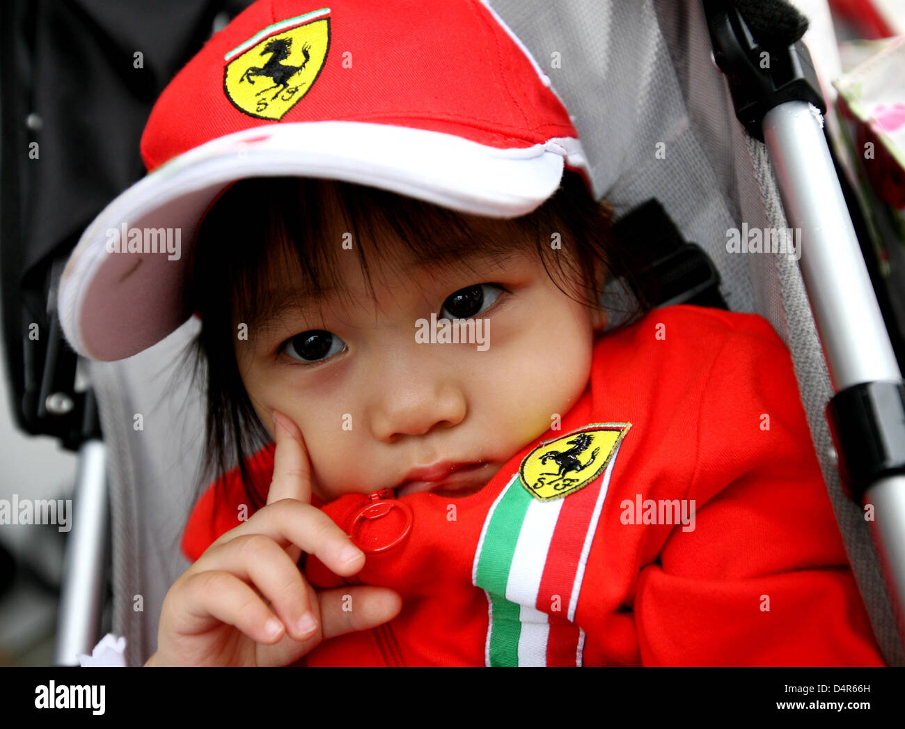 A toddler wearing a Scuderia Ferrari outfit is seen at Suzuka Circuit ...