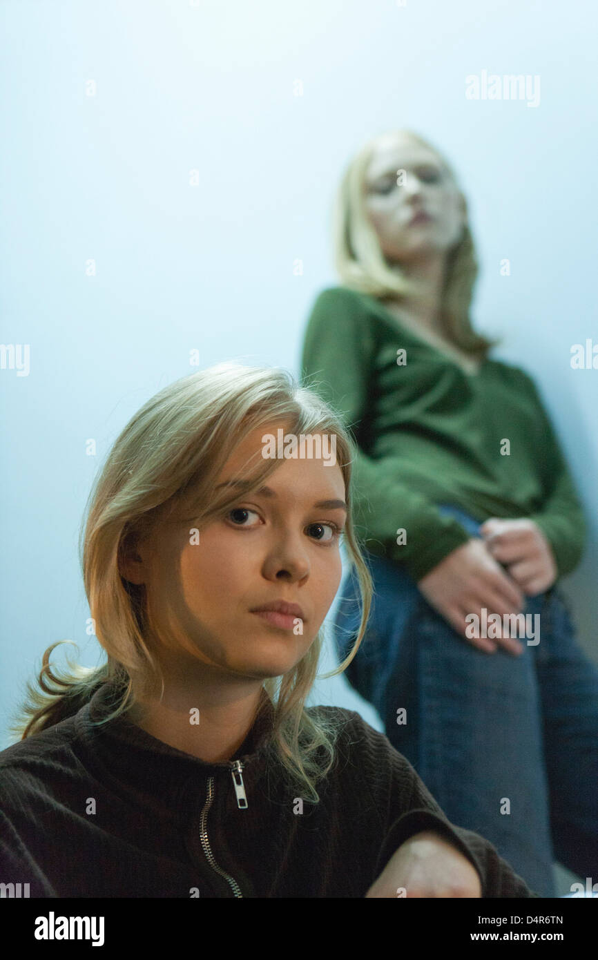 Teenage girl looking at camera, friend in background Stock Photo - Alamy