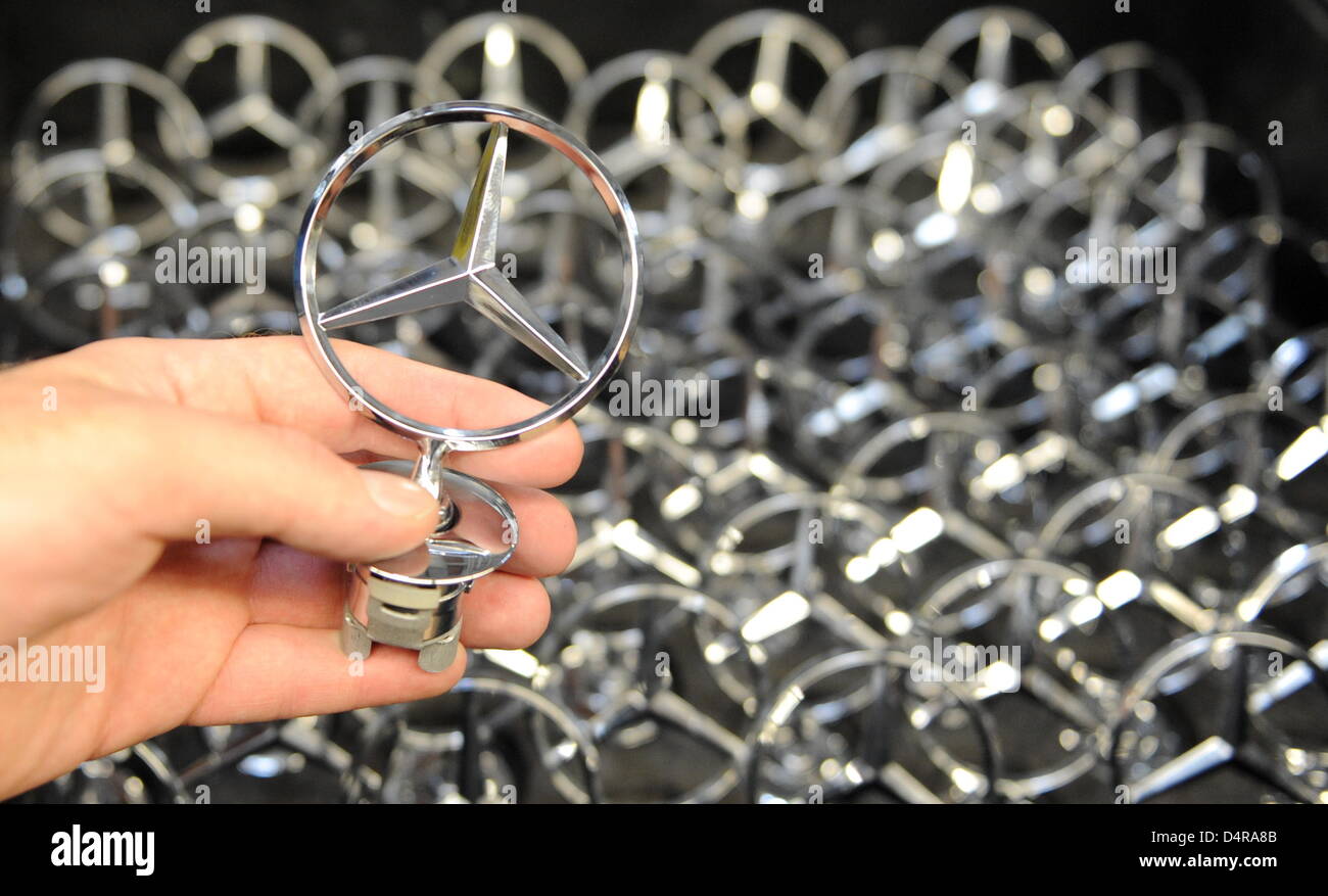A worker holds a Mercedes-Benz star at the assembly line for the E ...