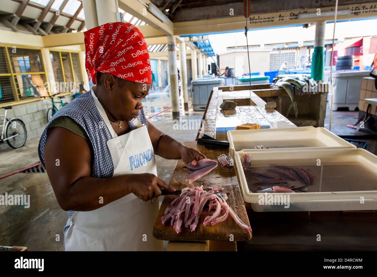A woman guts fresh flying fish in Bridgetown fish market, Barbados ...