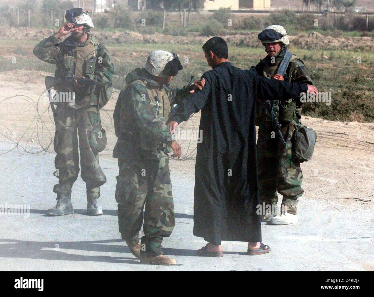 Military policemen of the US Marine control a civilian, on 3 April 2003 ...