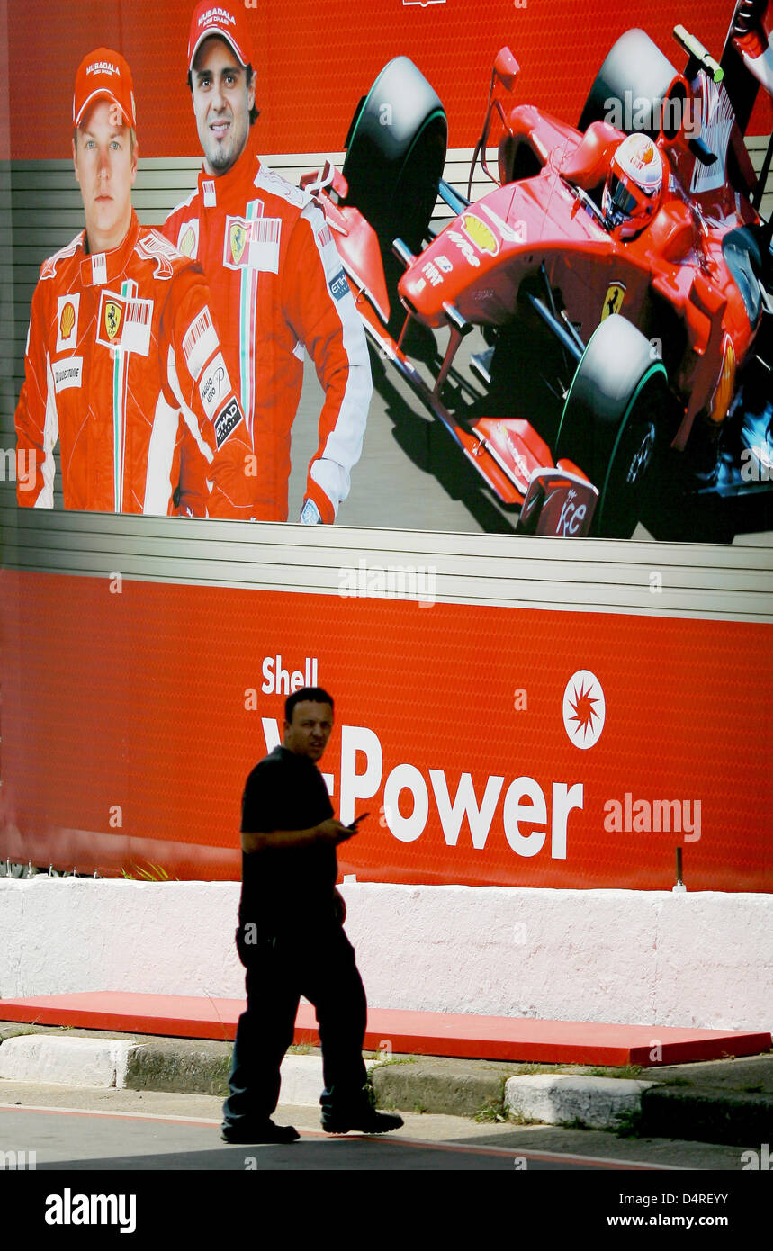 A worker passes a billboard showing Scuderia Ferrari?s drivers Kimi ...