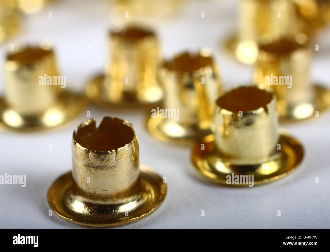 Brass craft eyelets on white background Stock Photo - Alamy