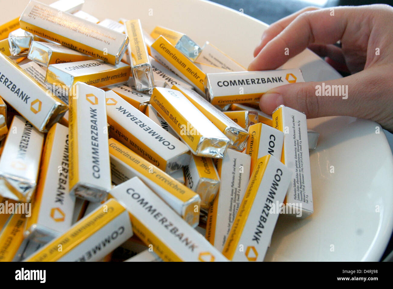 A woman takes a peppermint candy with the new logo of Commerzbank ...