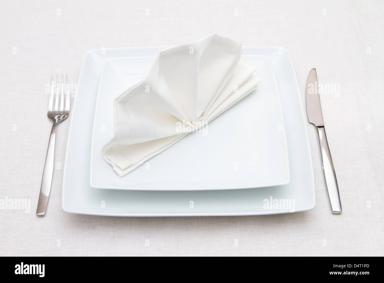 Place setting with white plates and white folded napkin Stock Photo - Alamy