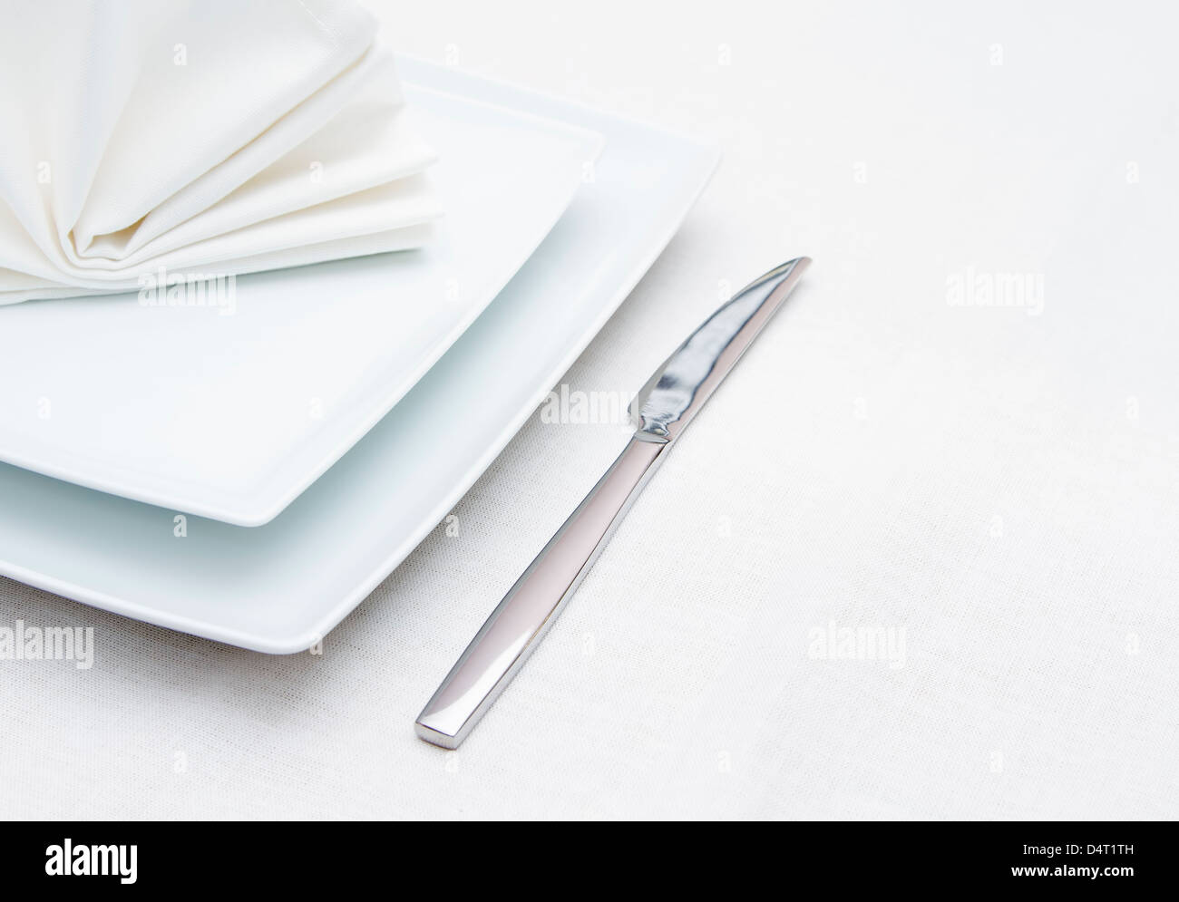 White place setting with knife and folded white napkin Stock Photo - Alamy