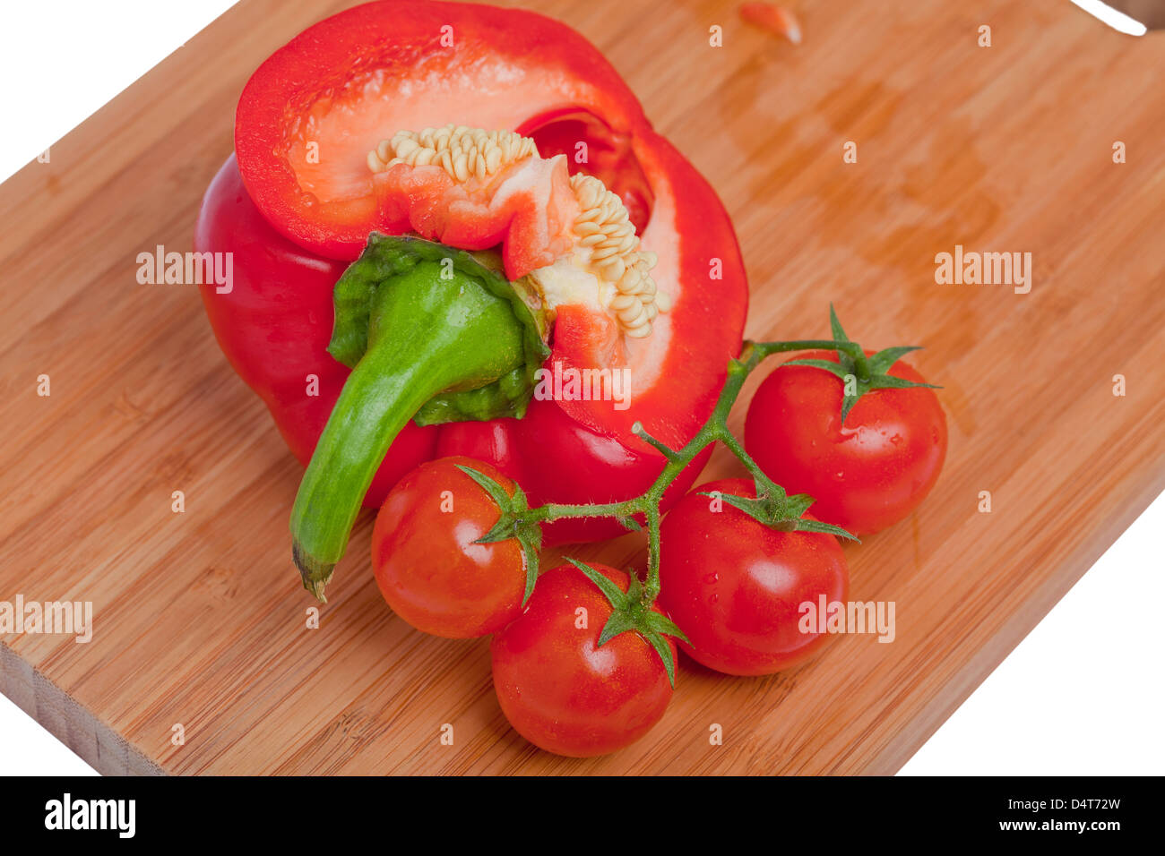 Sweet pepper cut open with visible seeds on a wooden board with cherry ...