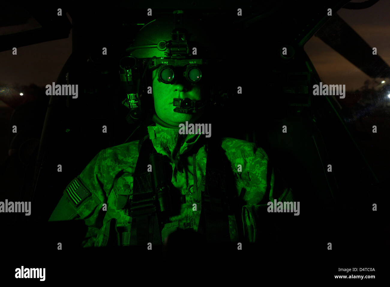 A pilot equipped with night vision goggles in the cockpit of an AH-64 ...
