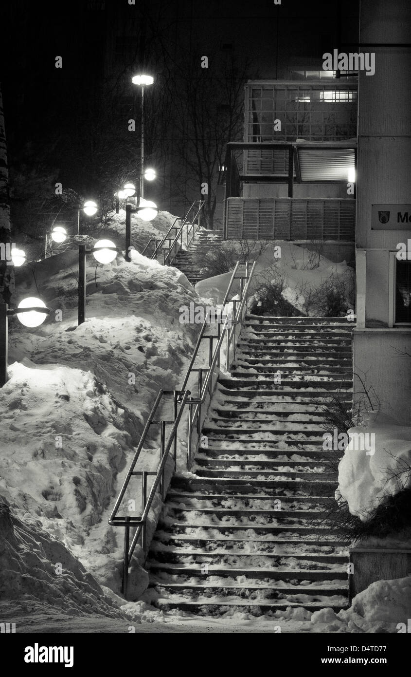 Stairs partially covered in snow illuminated from the side by street ...