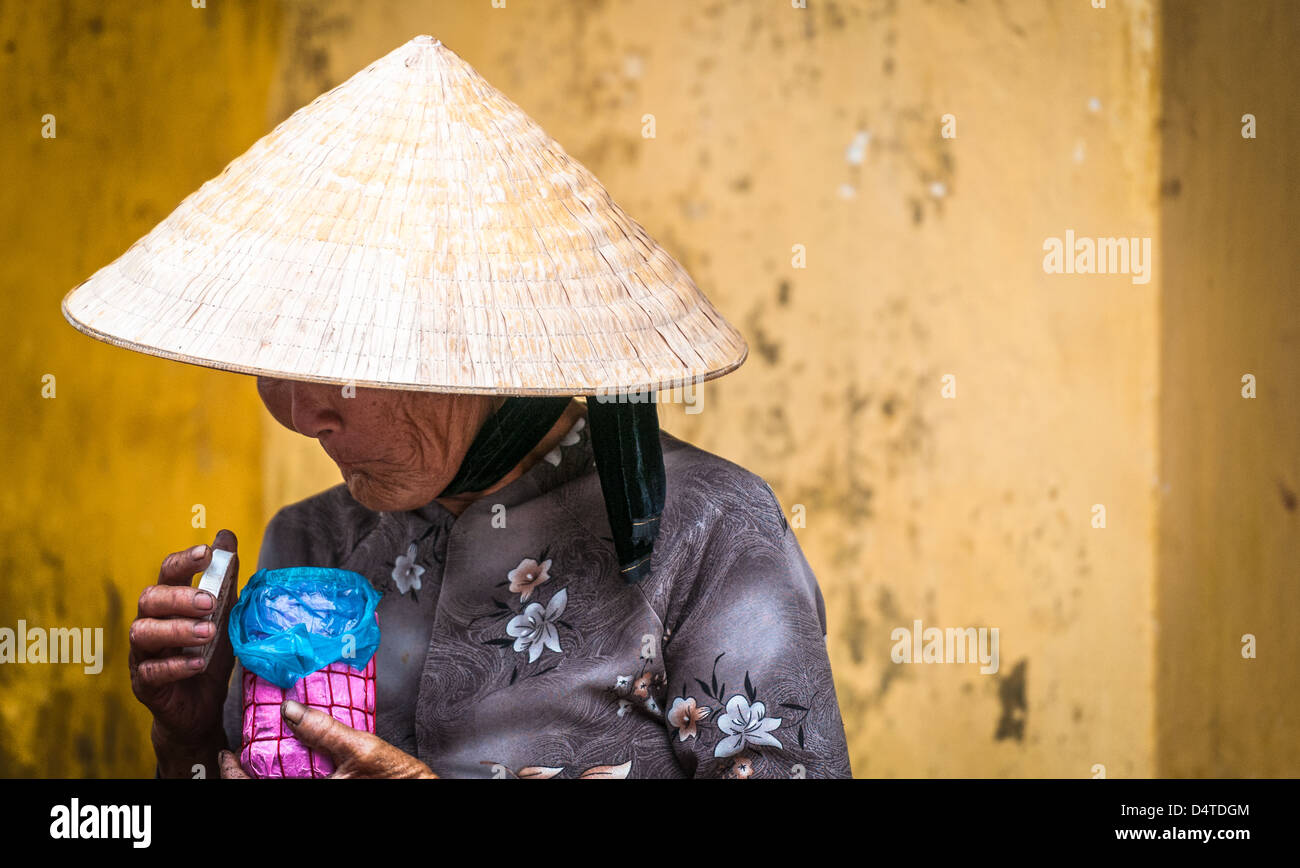 Old poor woman wearing conical hat and traditional asian dress ...
