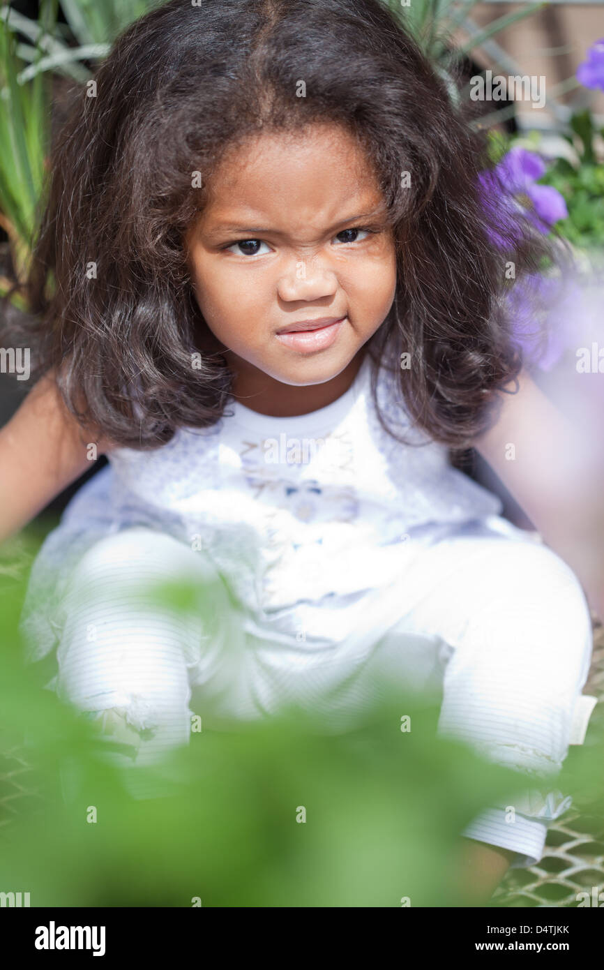 Frowning girl sitting in plants Stock Photo - Alamy