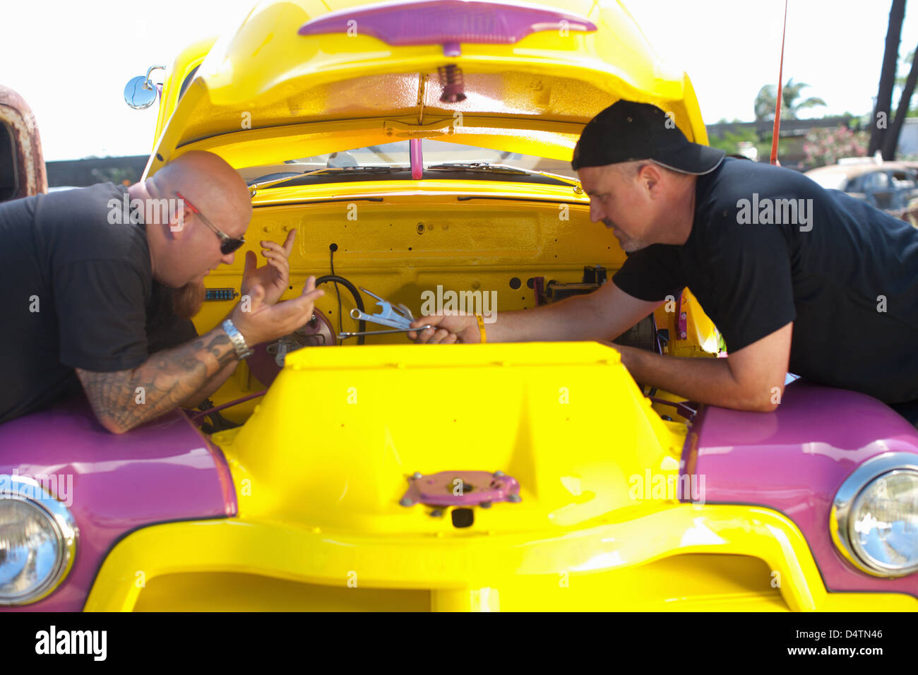 Mechanics working on colorful car Stock Photo - Alamy