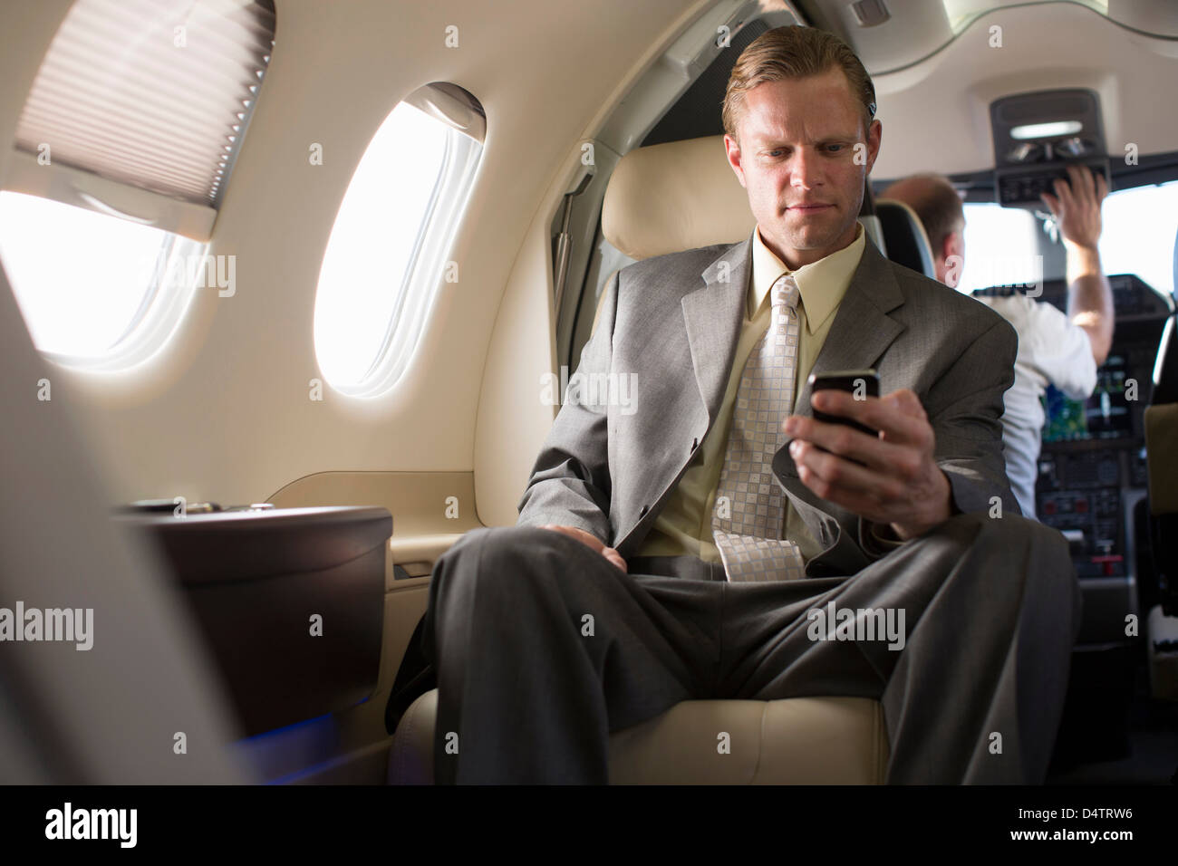 Businessman using cell phone on airplane Stock Photo - Alamy