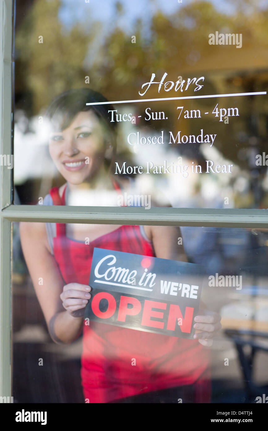 Waitress putting open sign in window Stock Photo - Alamy