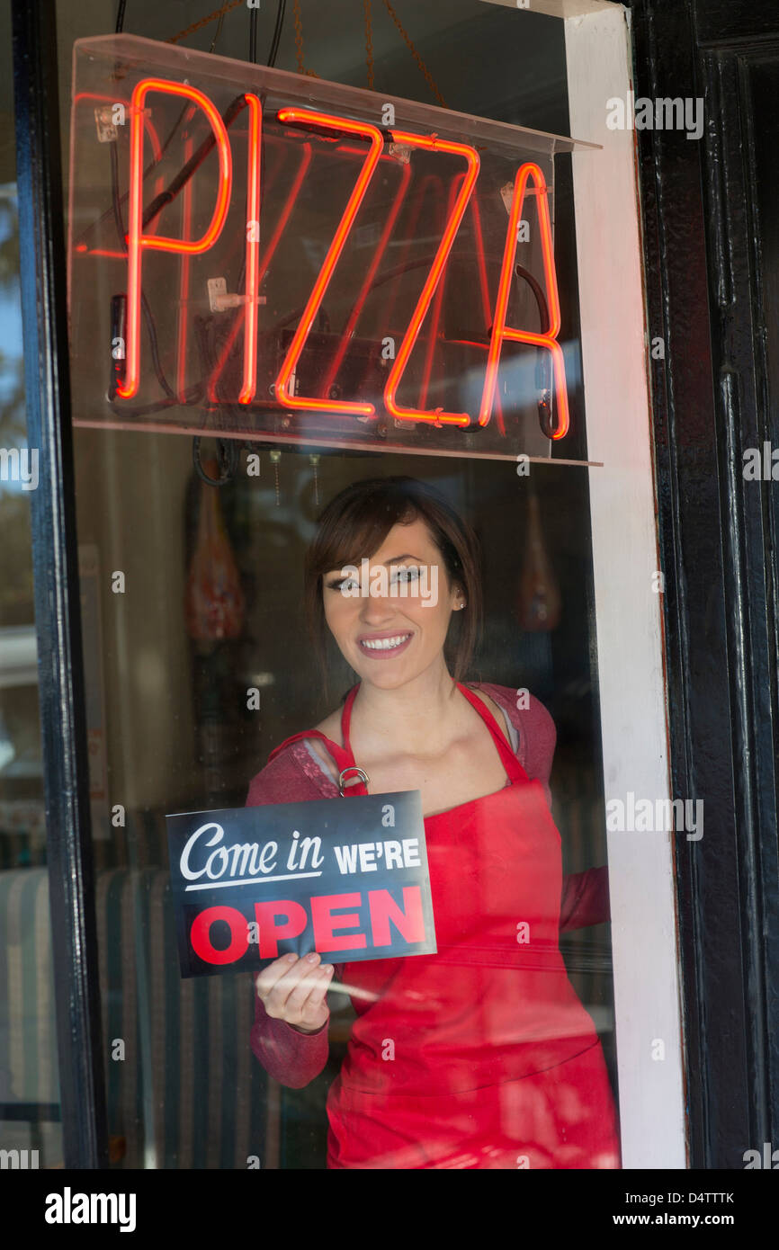 Woman putting open sign in window Stock Photo - Alamy
