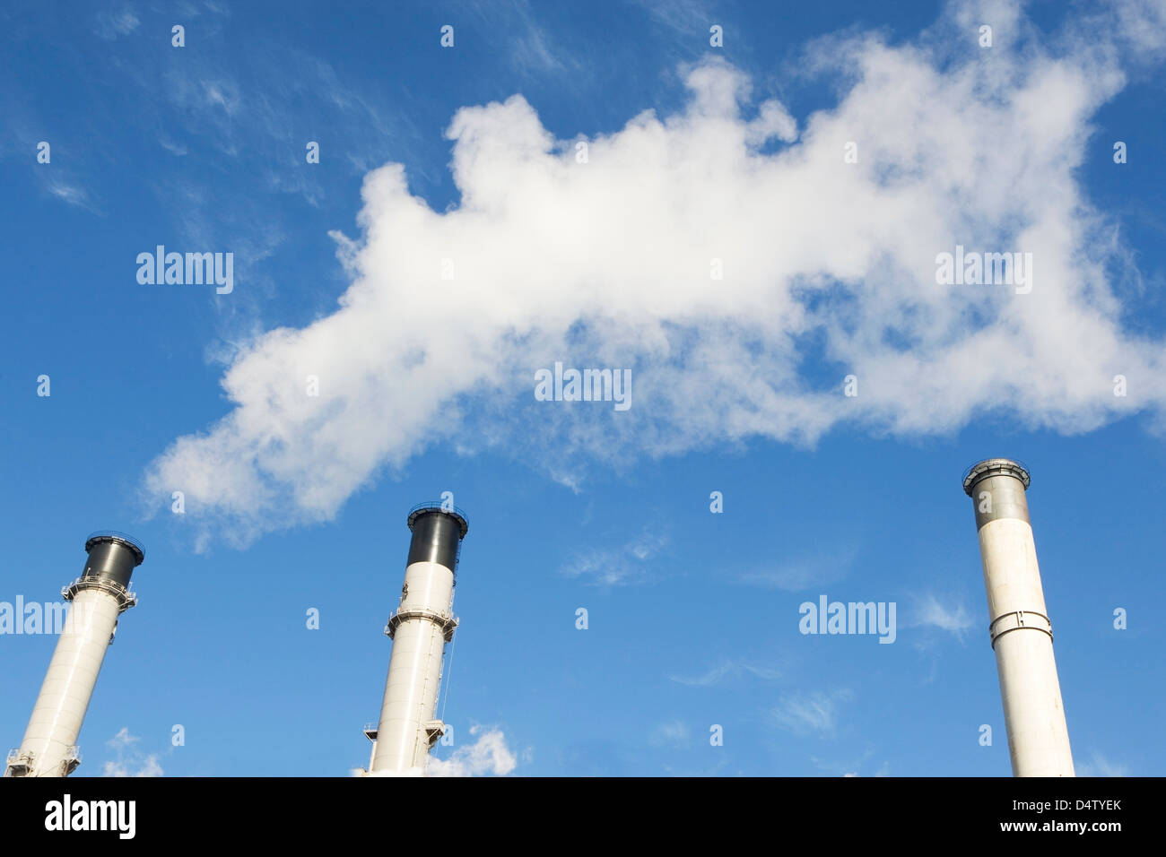 Factory smokestacks against blue sky Stock Photo - Alamy