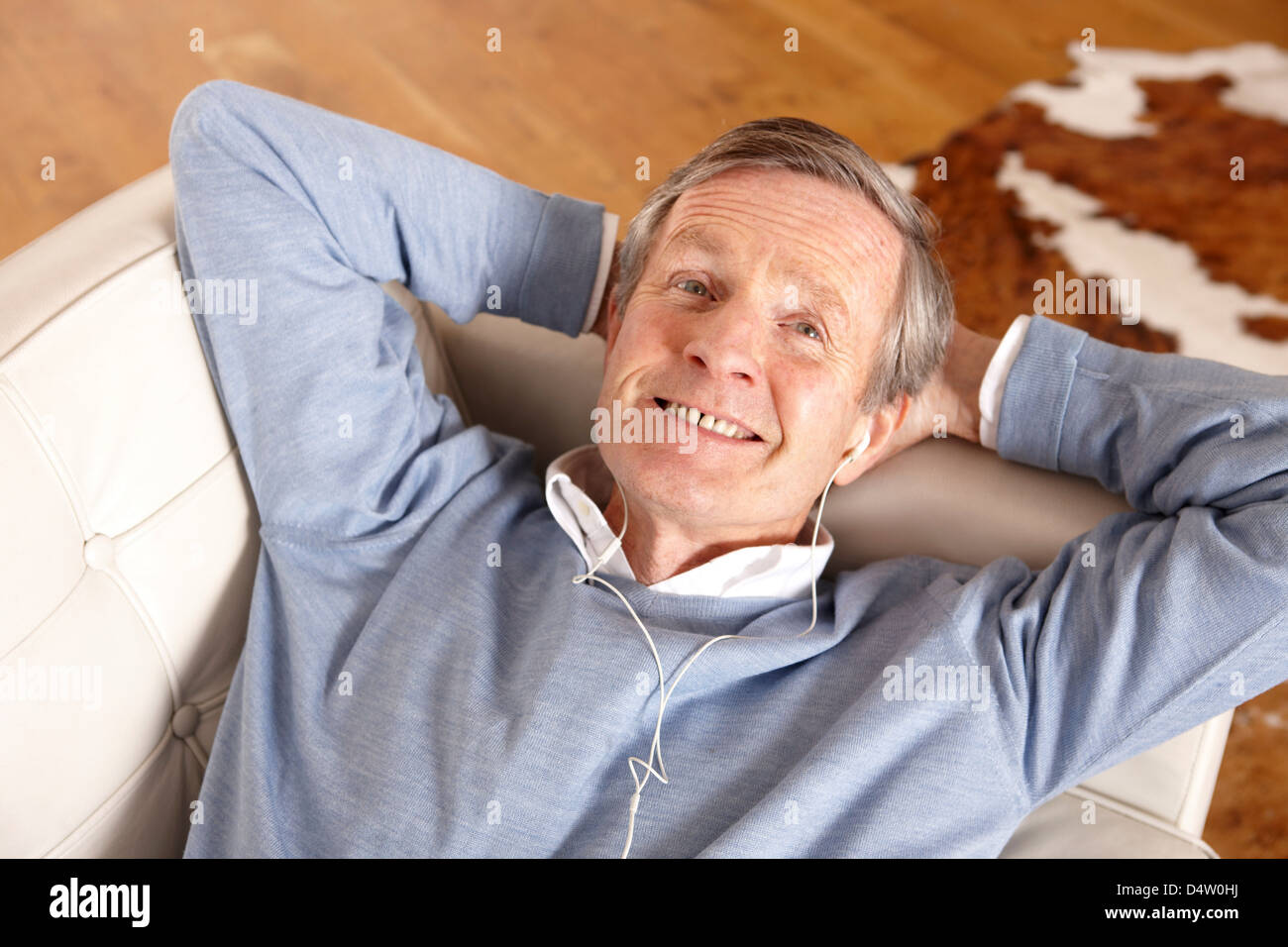 Older man listening to earphones on sofa Stock Photo - Alamy