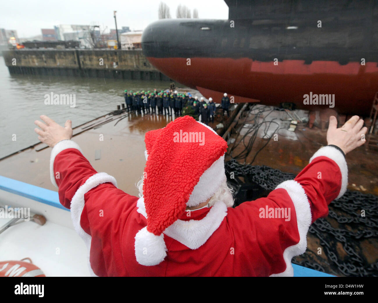 A Santa Claus throws a fir tree onto a ship in the harbour of Hamburg ...