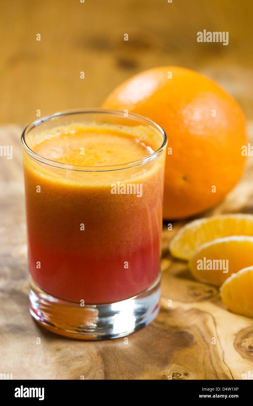 A glass of freshly squeezed blood orange juice with whole fruit and ...