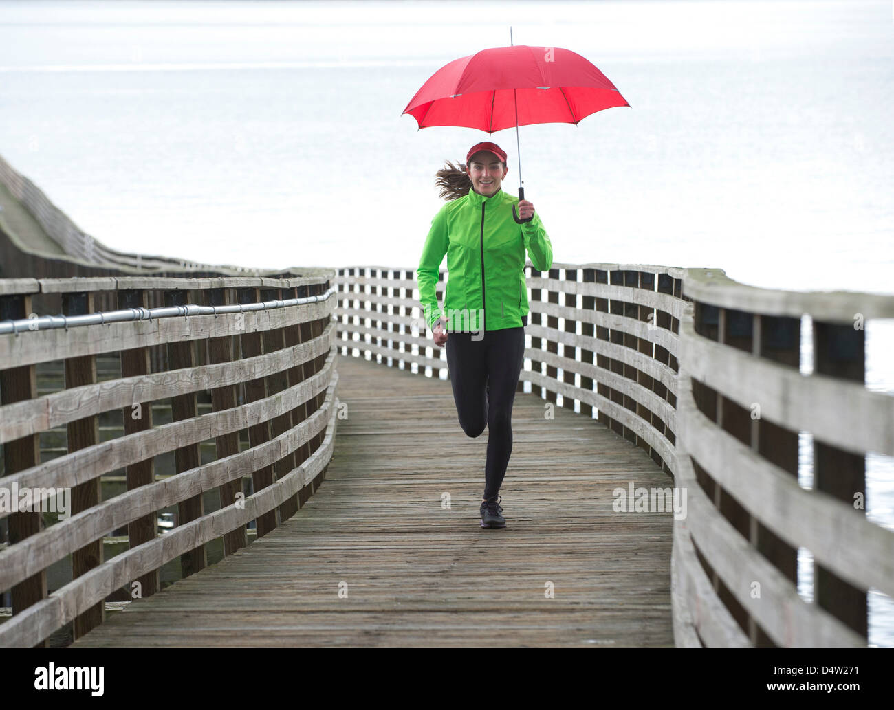 Woman running under umbrella Stock Photo - Alamy