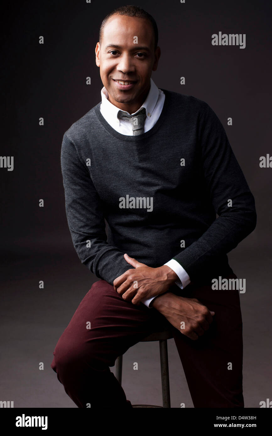 Smiling man sitting on stool Stock Photo - Alamy