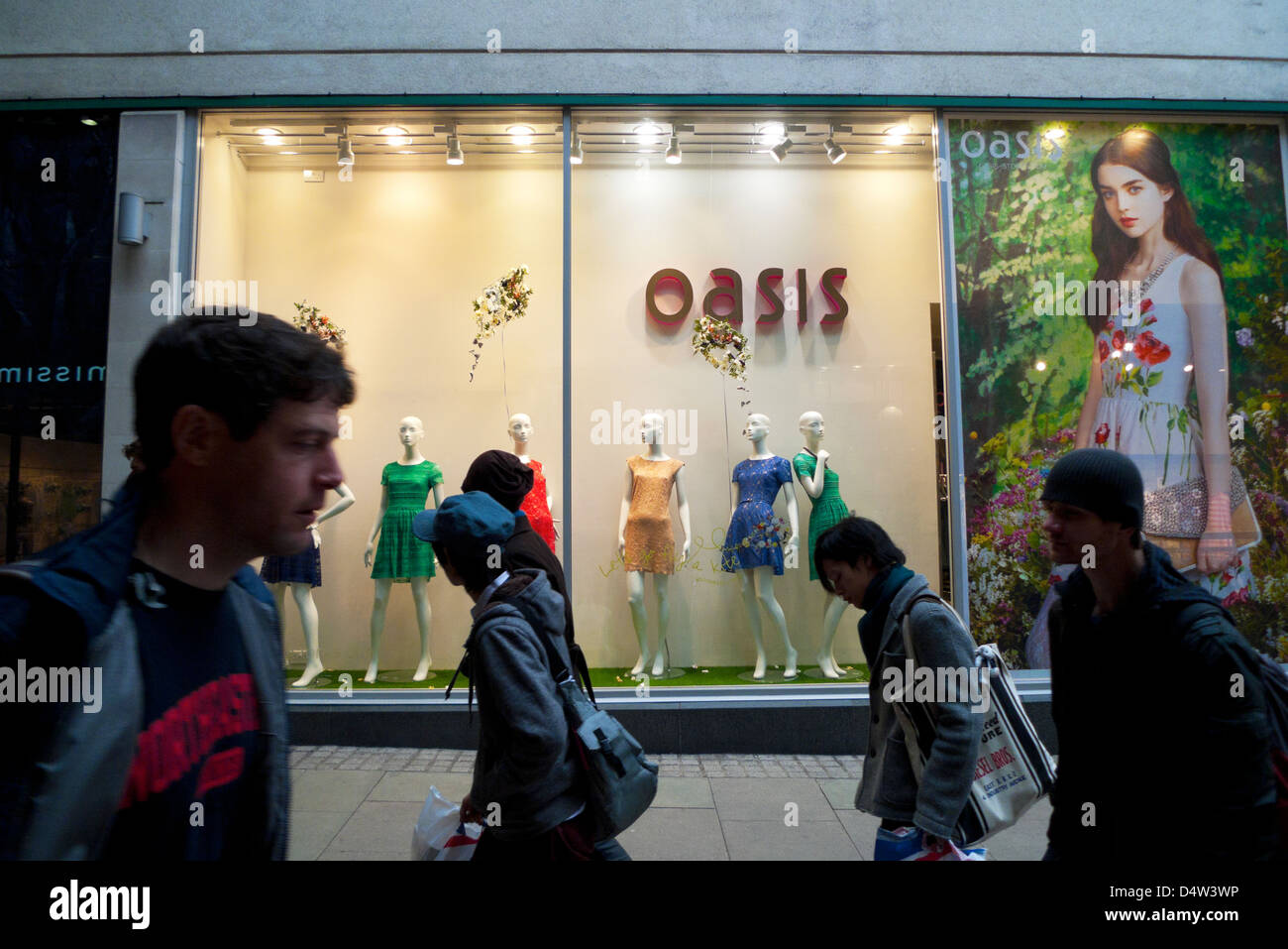 Shoppers walking past spring display in Oasis store with heads bowed in ...