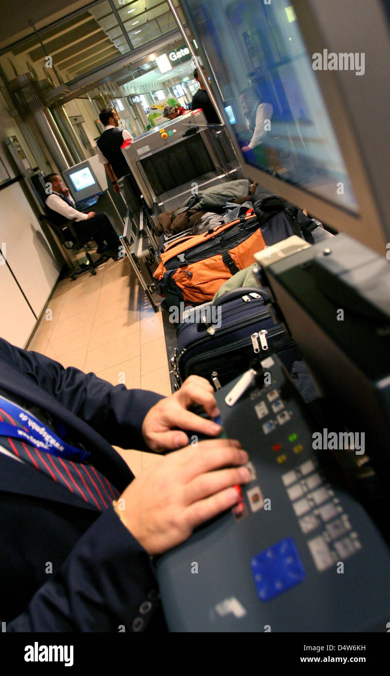 Security staff follows his monitor at the hand-luggage check during a ...
