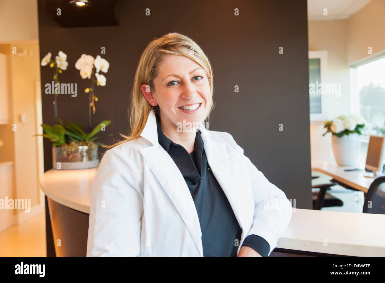 Doctor smiling at receptionist's desk Stock Photo - Alamy