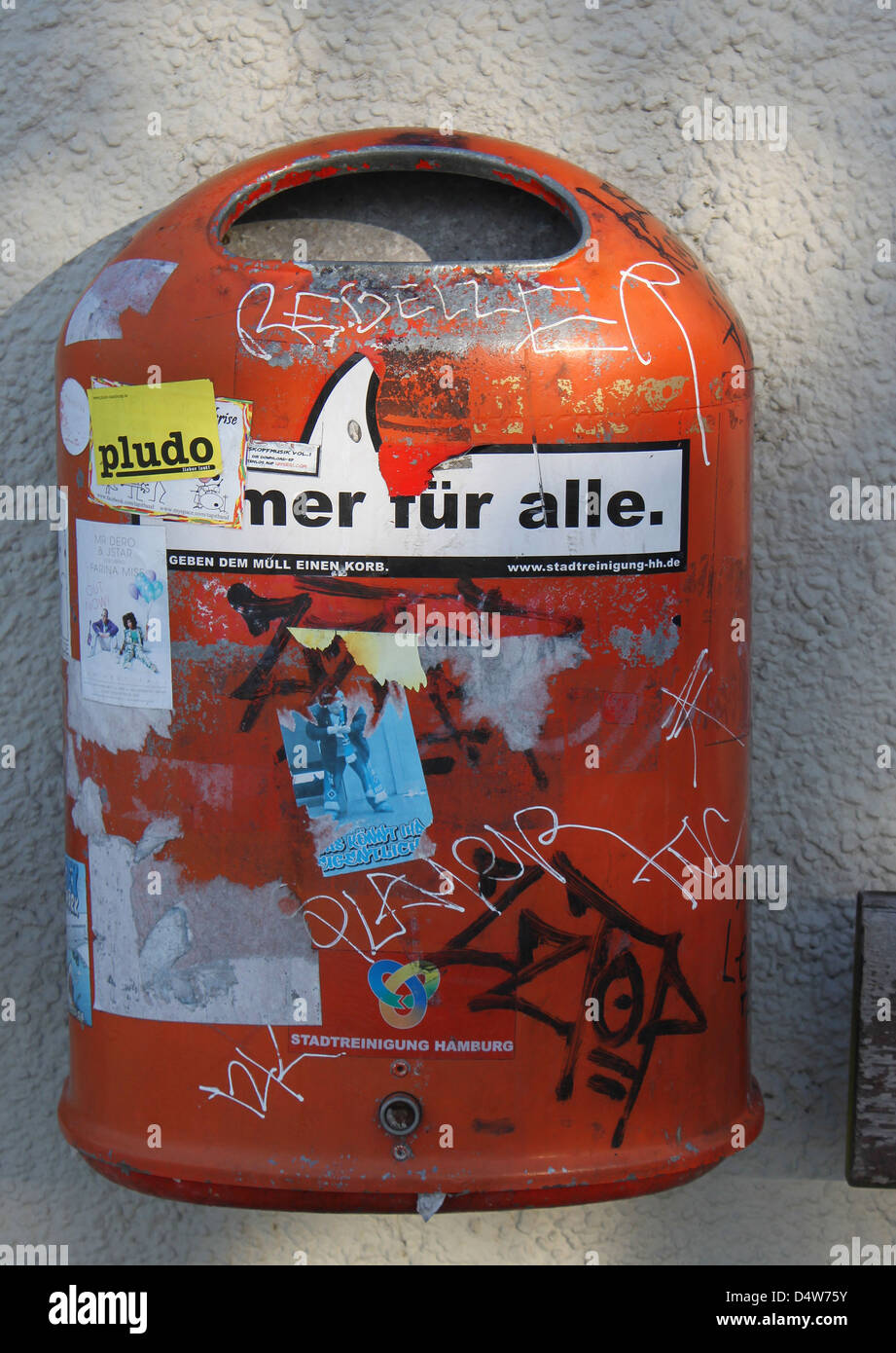 A photograph of a bright red bin with stickers and graffiti in Hamburg ...