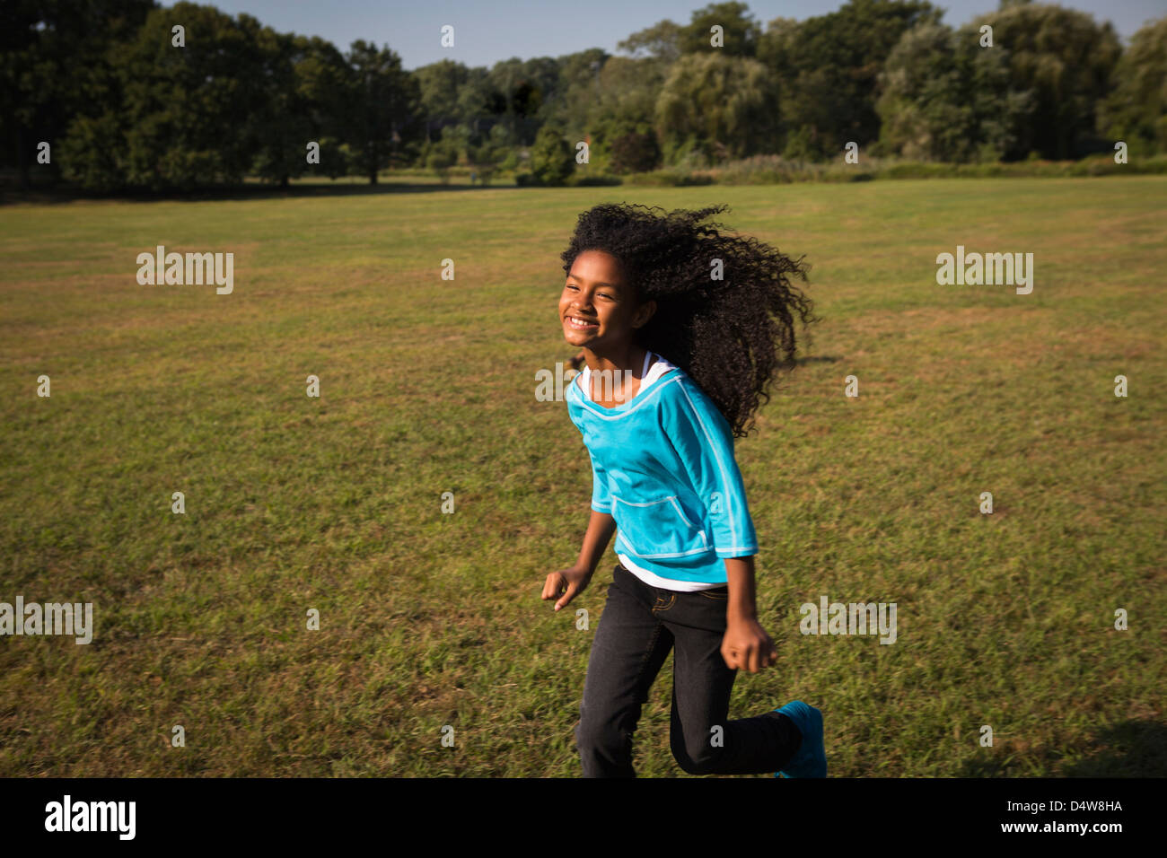 Smiling girl running in field Stock Photo - Alamy