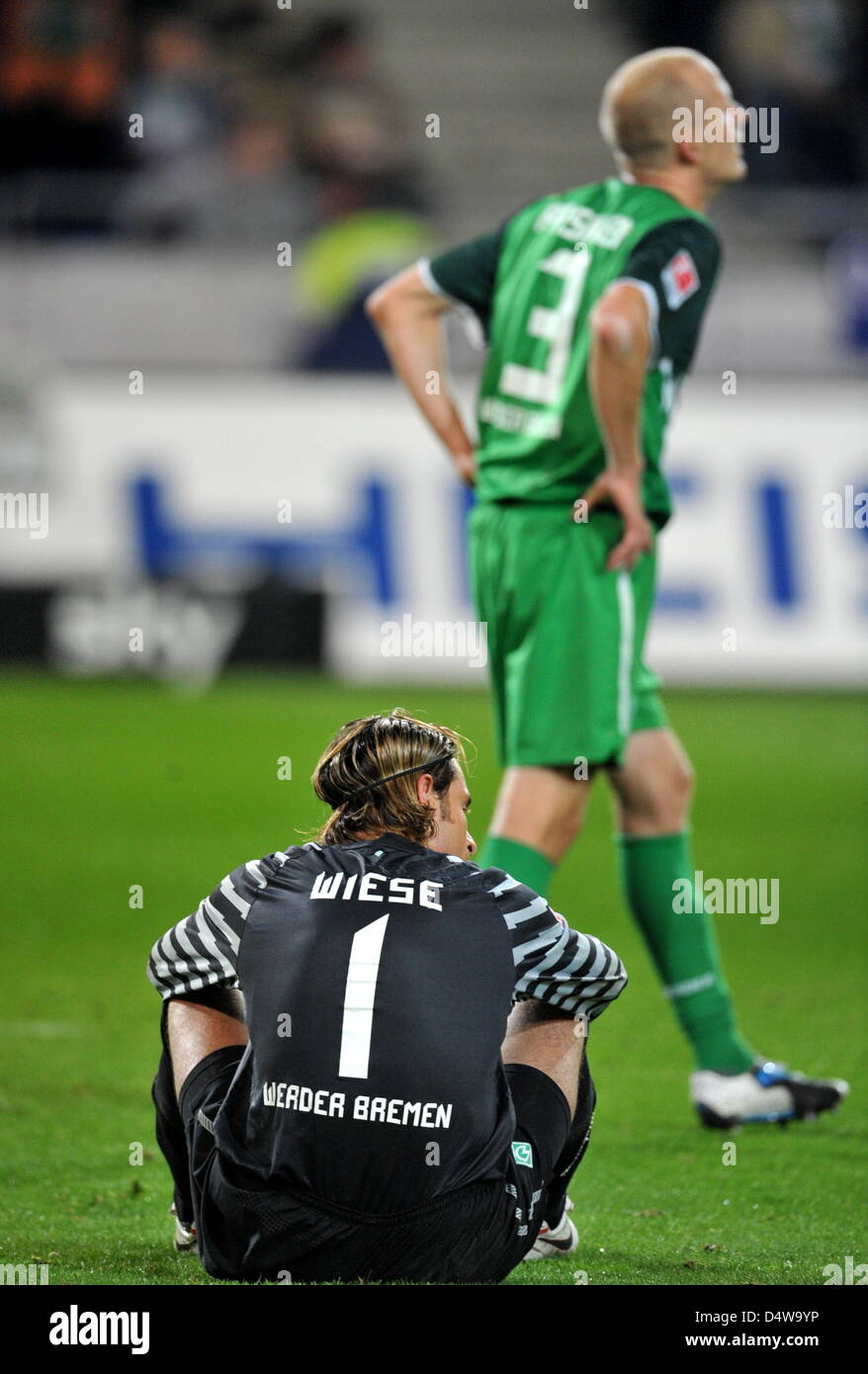 Bremen's goalkeeper Tim Wiese sits on the field, behind Petri Pasanen ...