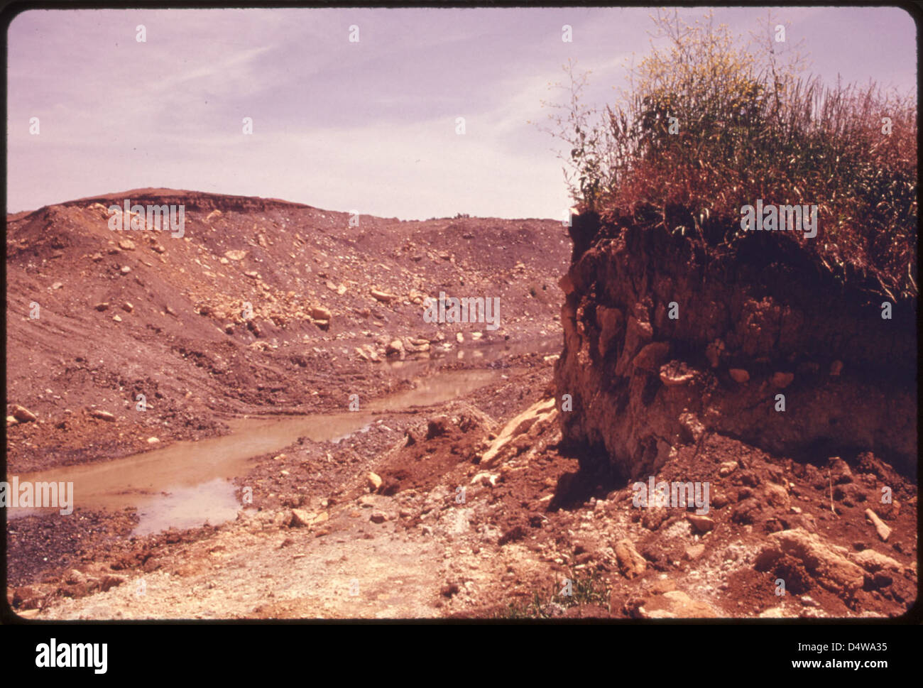 A photograph from July 1974 showing water pooling in a trench caused by ...