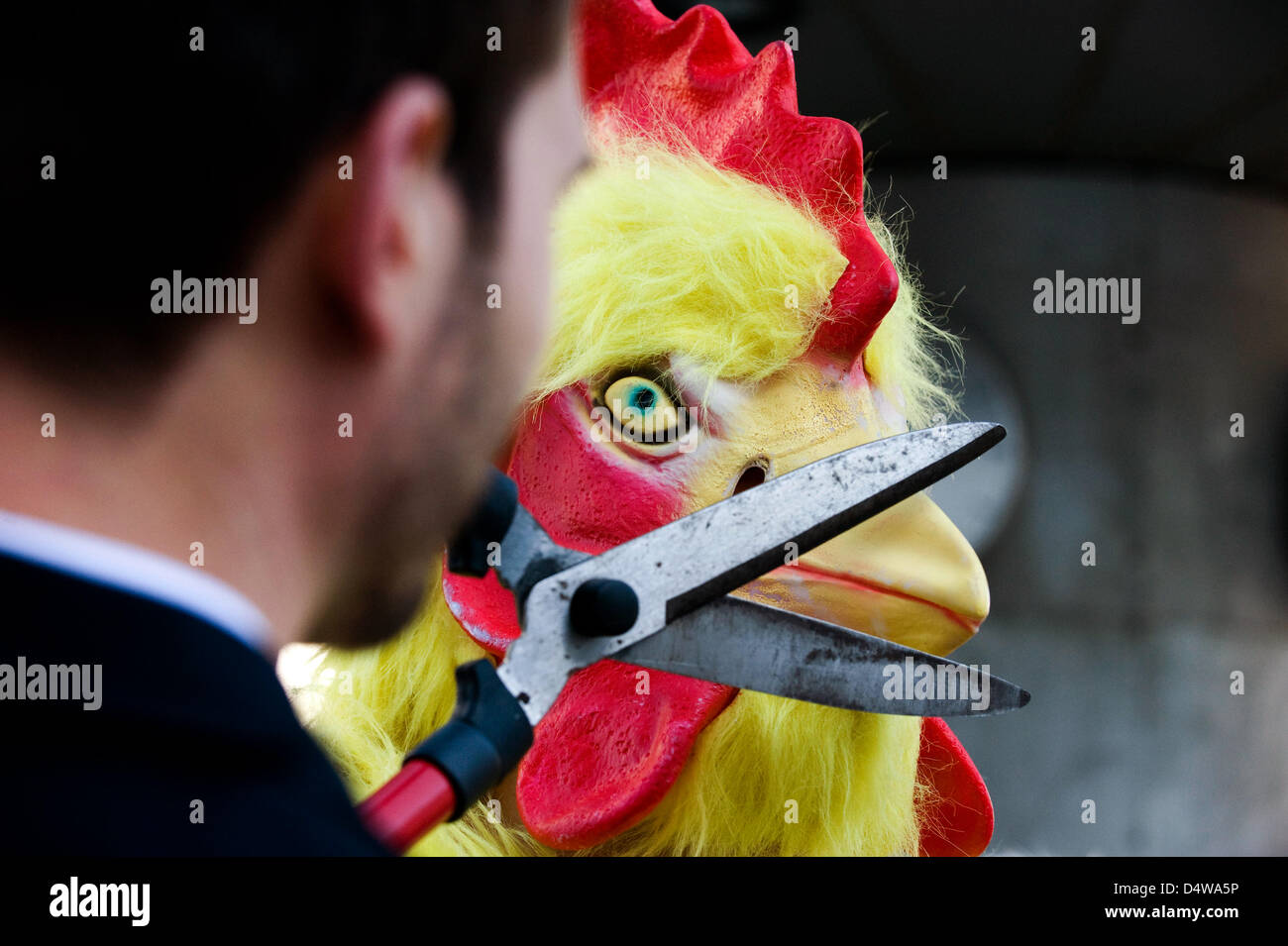 With oversized scissors, a man imitates to cut off the beak of a model ...