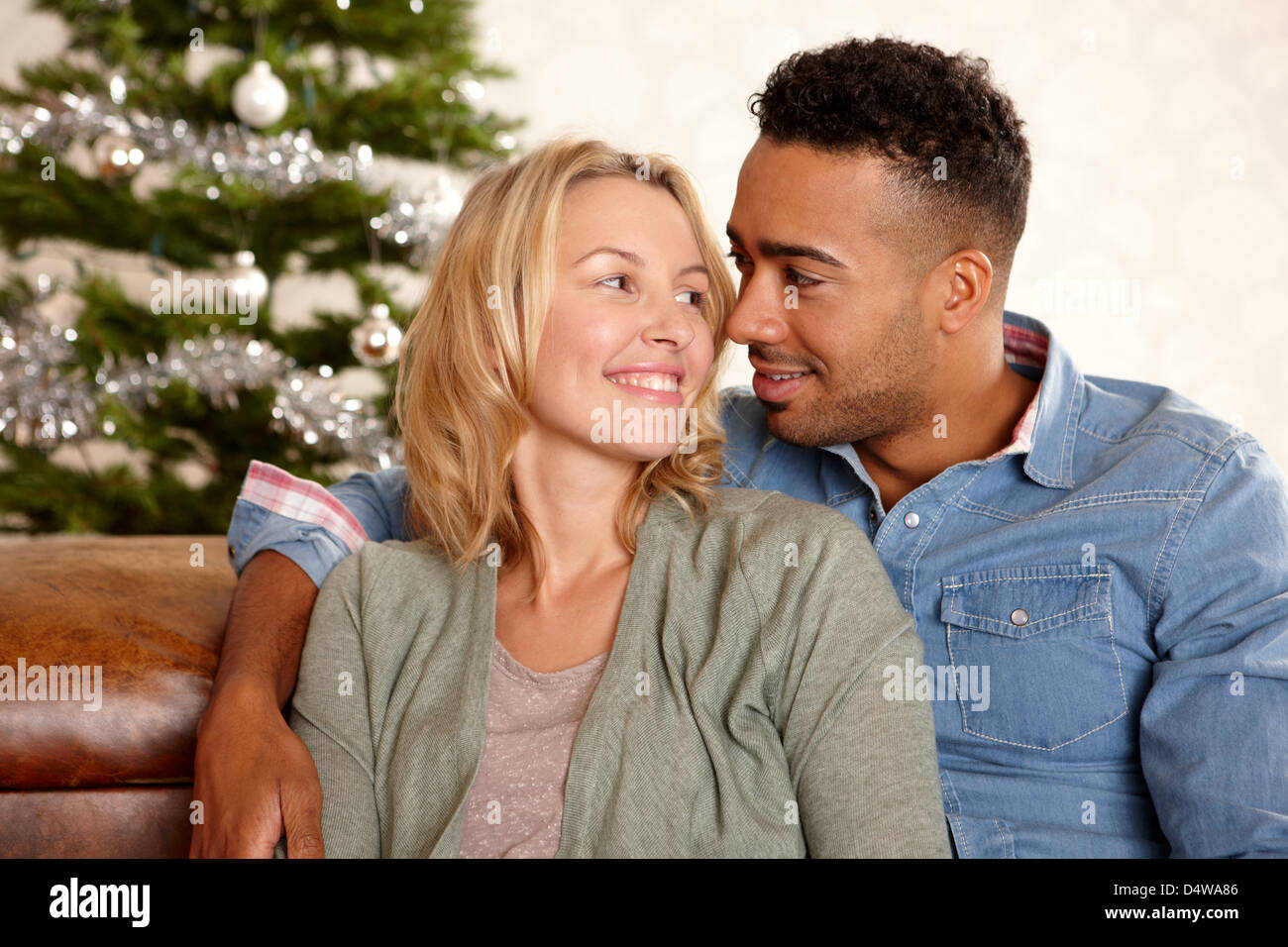Couple smiling together on sofa Stock Photo - Alamy
