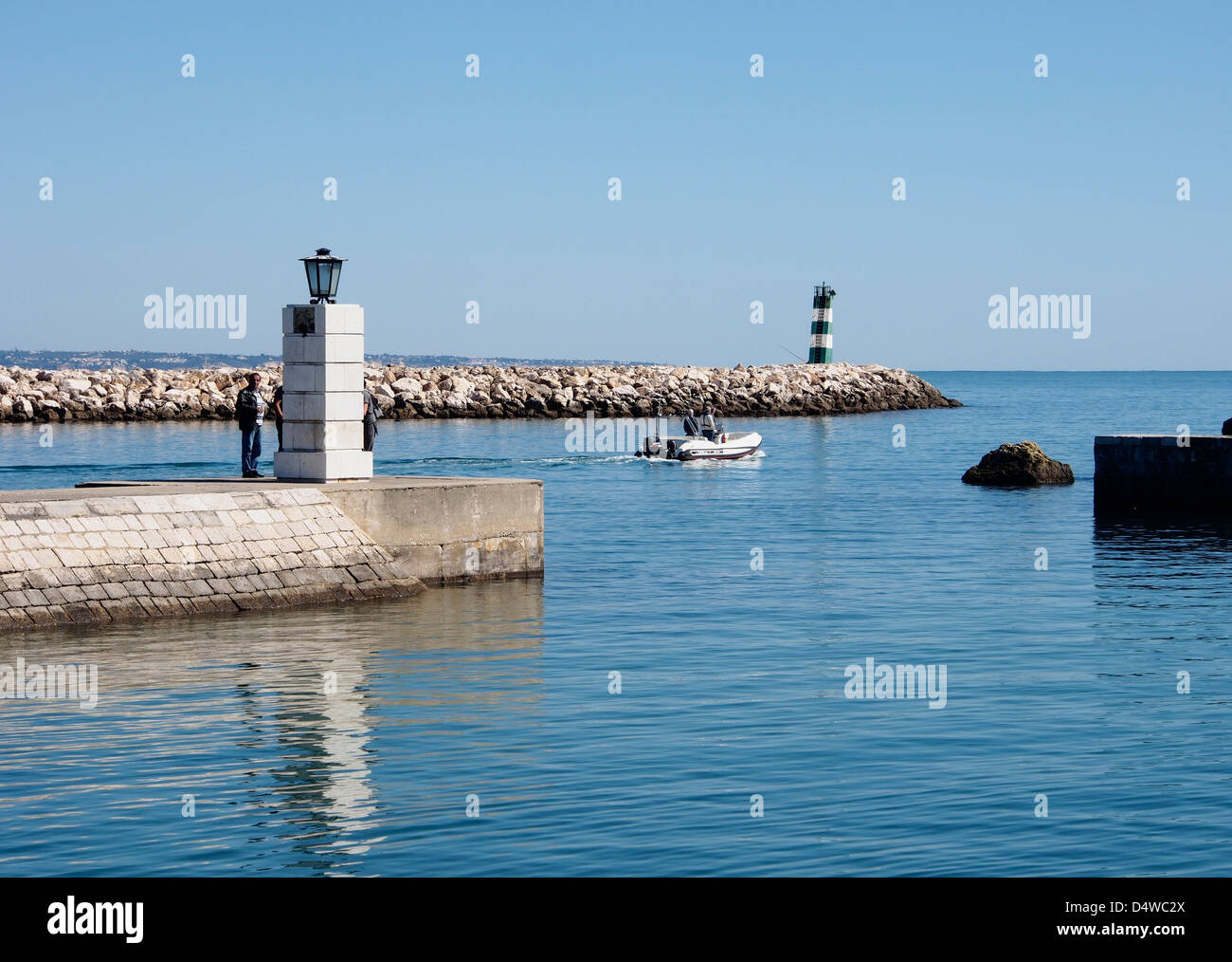 SMALL BOAT LEAVING HARBOUR ENTRANCE LAGOS PORTUGAL Stock Photo - Alamy