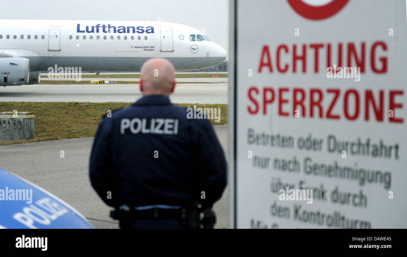 A police officer monitors the apron of the airport of Munich, Germany ...