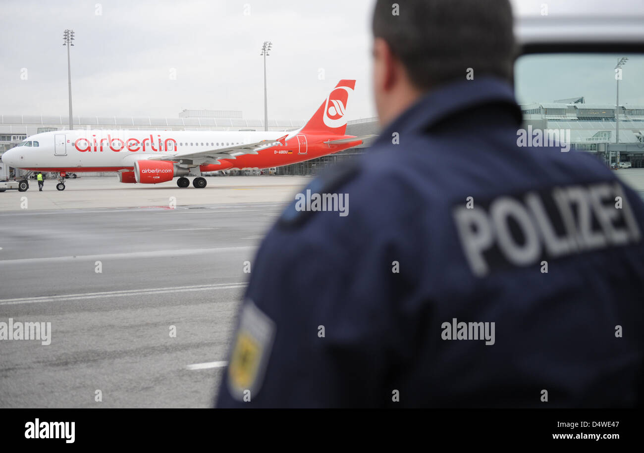 A police officer monitors the apron of the airport of Munich, Germany ...