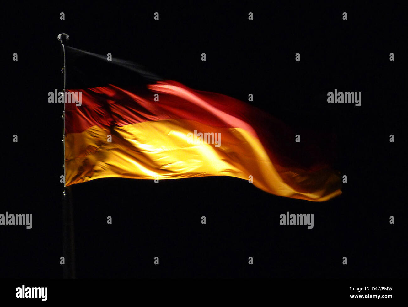 A night shot shows a waving German national flag in front of the ...