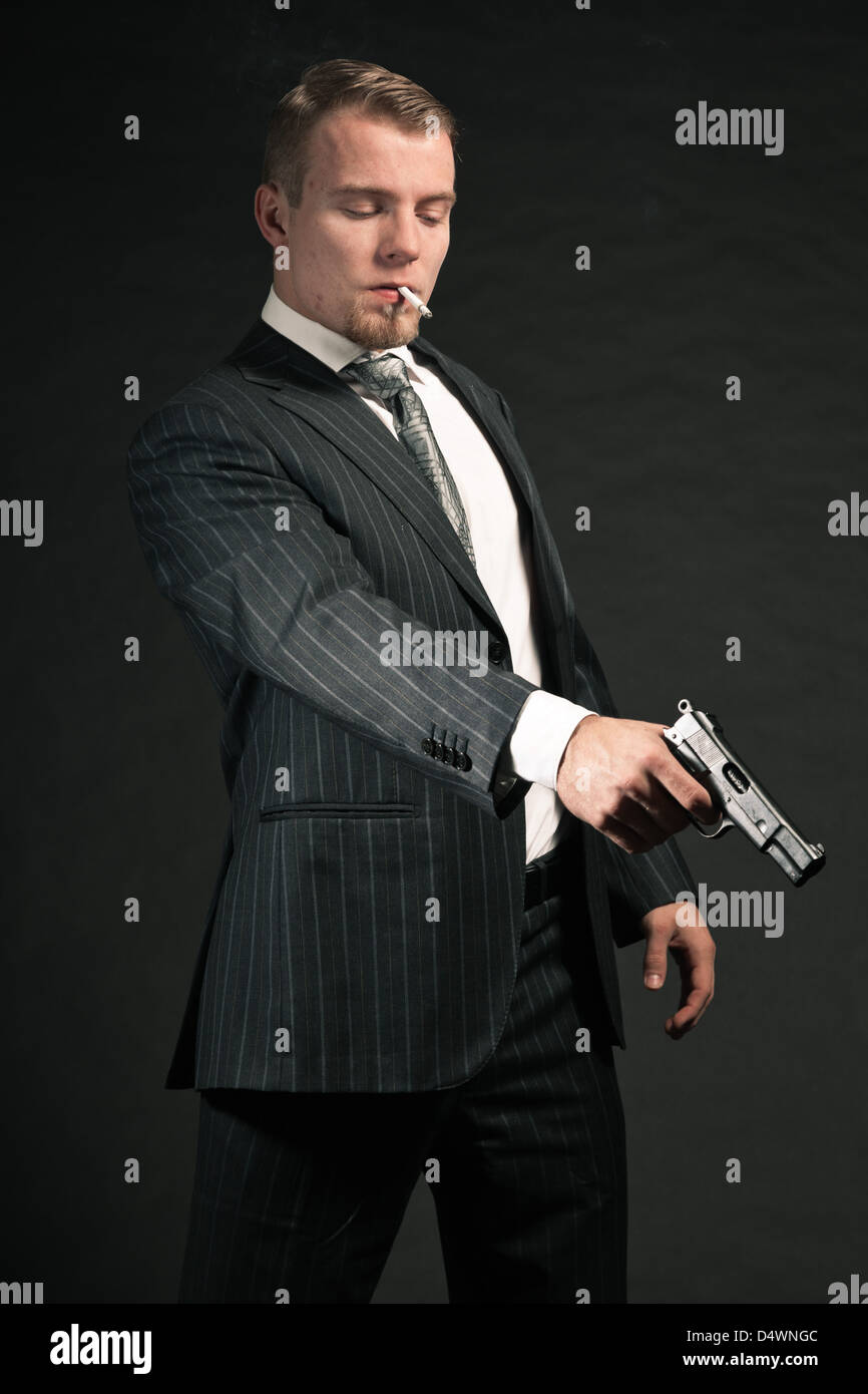 Man in suit shooting with gun. Smoking cigarette. Studio shot Stock ...
