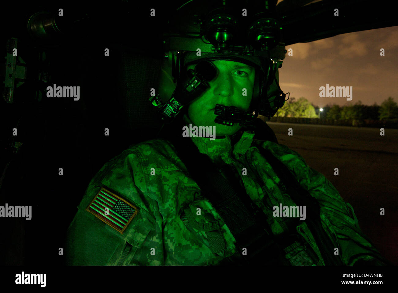 A pilot equipped with night vision goggles in the cockpit of an AH-64 ...