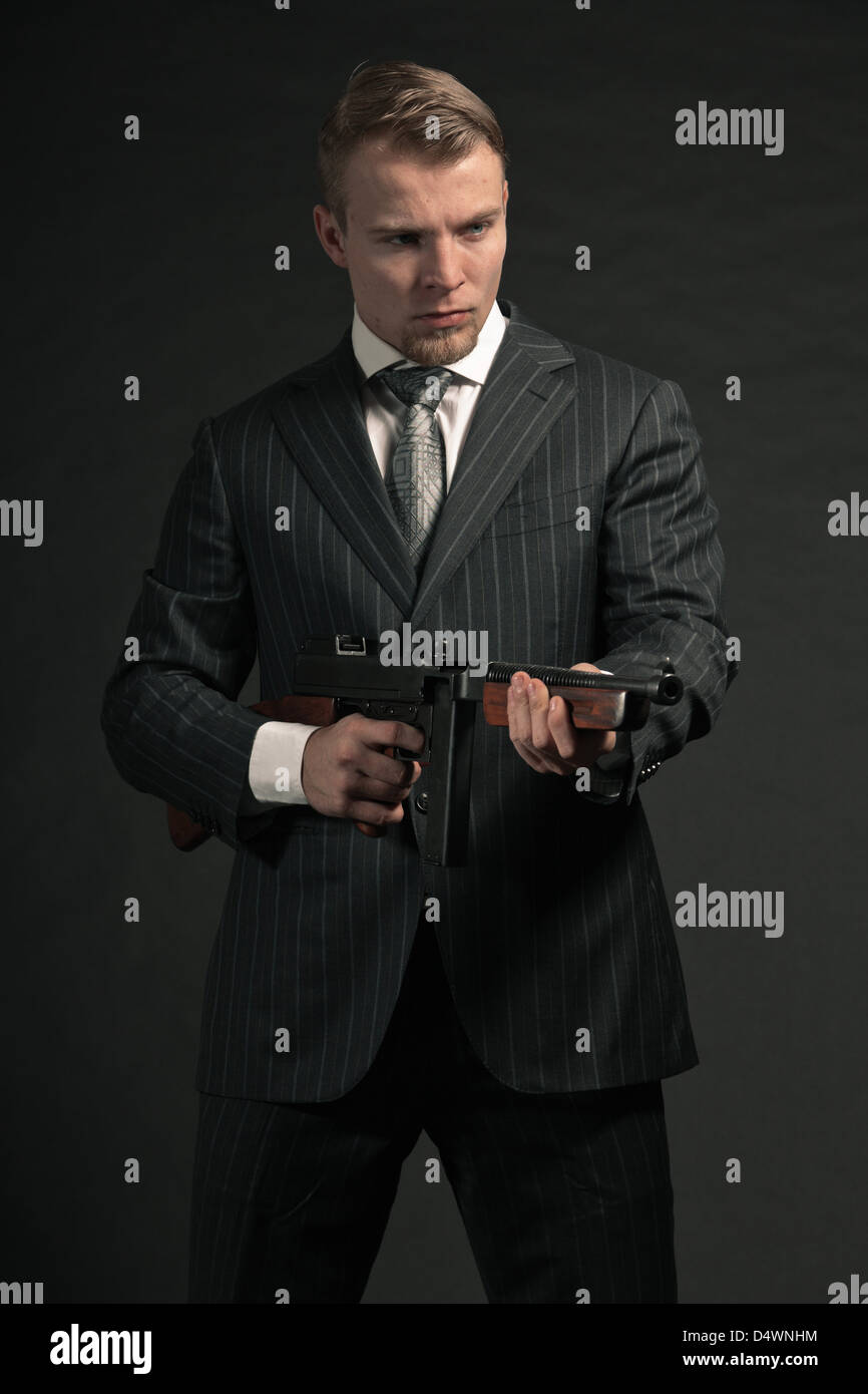 Man in suit shooting with rifle. Studio shot against black Stock Photo ...