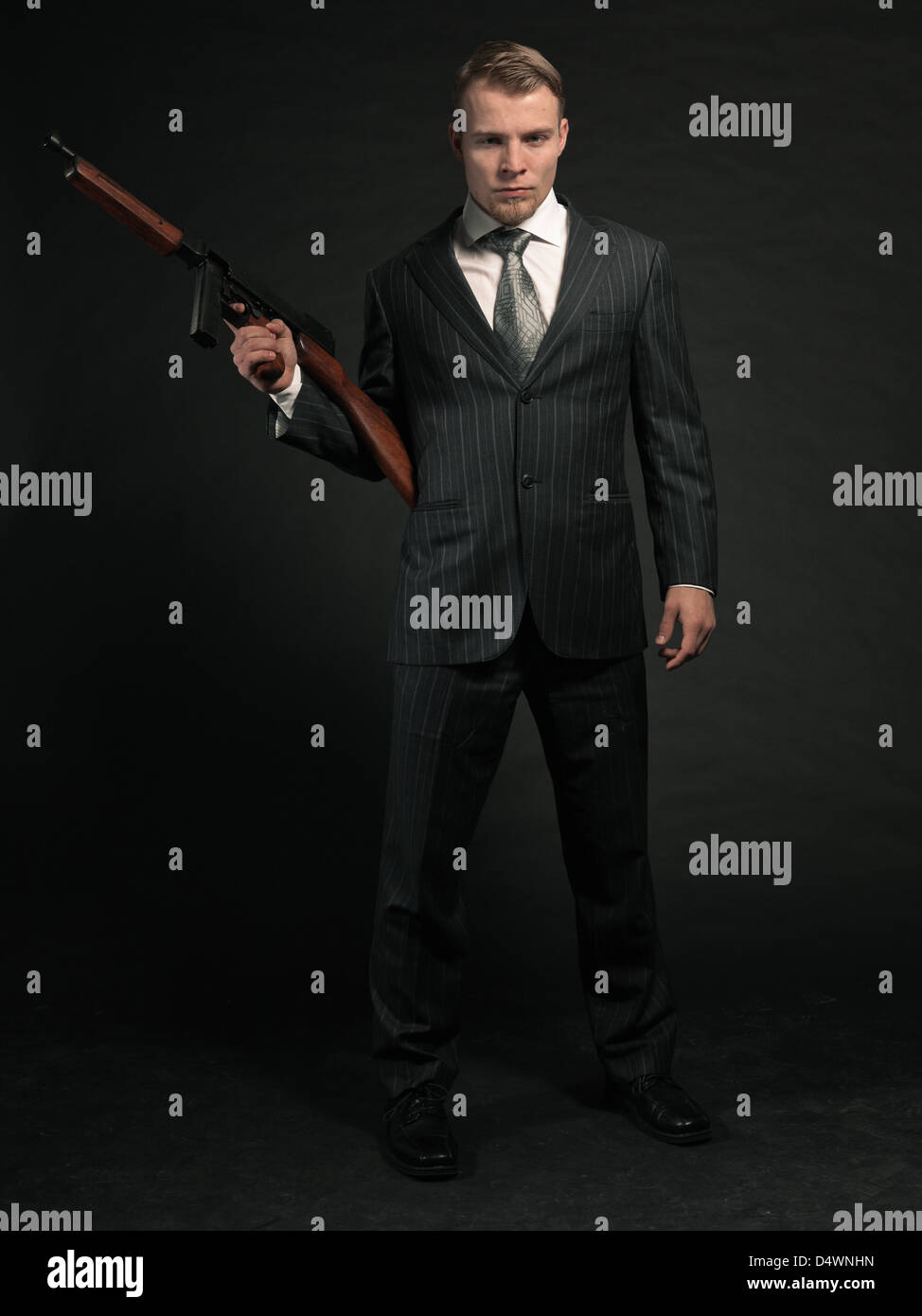 Man in suit shooting with rifle. Studio shot against black Stock Photo ...