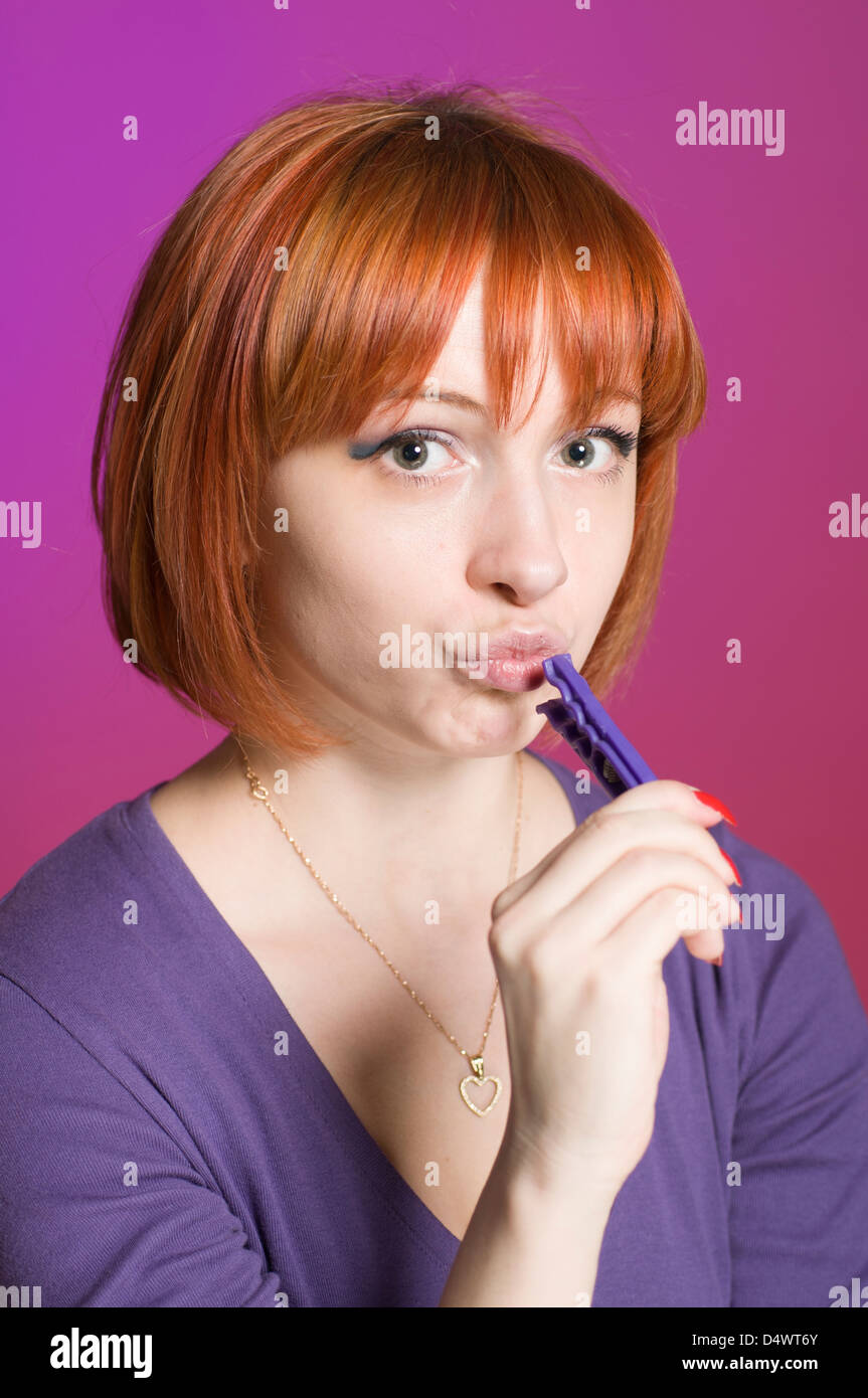 Portrait of beautiful red woman with clothespin posing at the studio ...