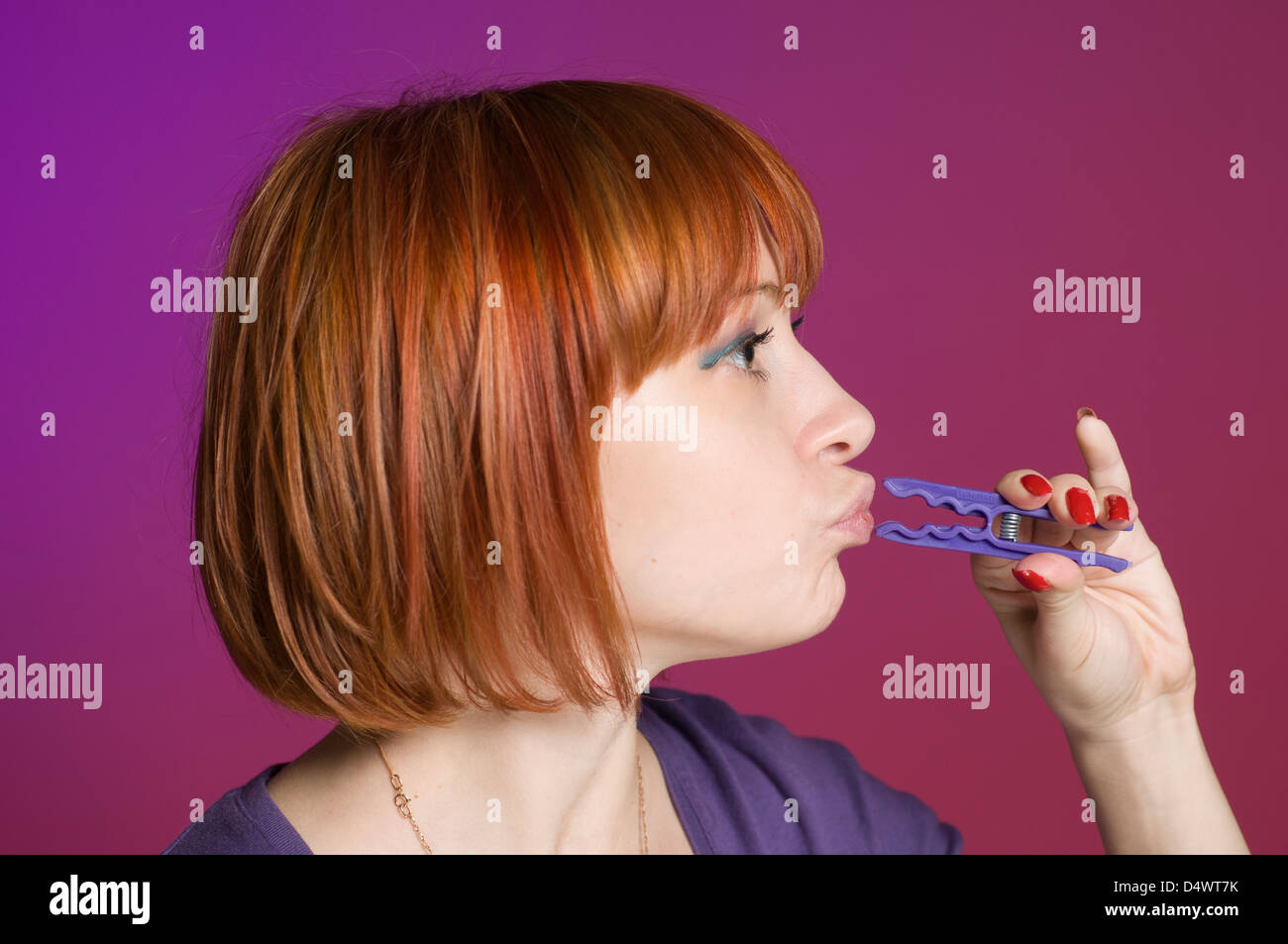 Portrait of beautiful red woman with clothespin posing at the studio ...
