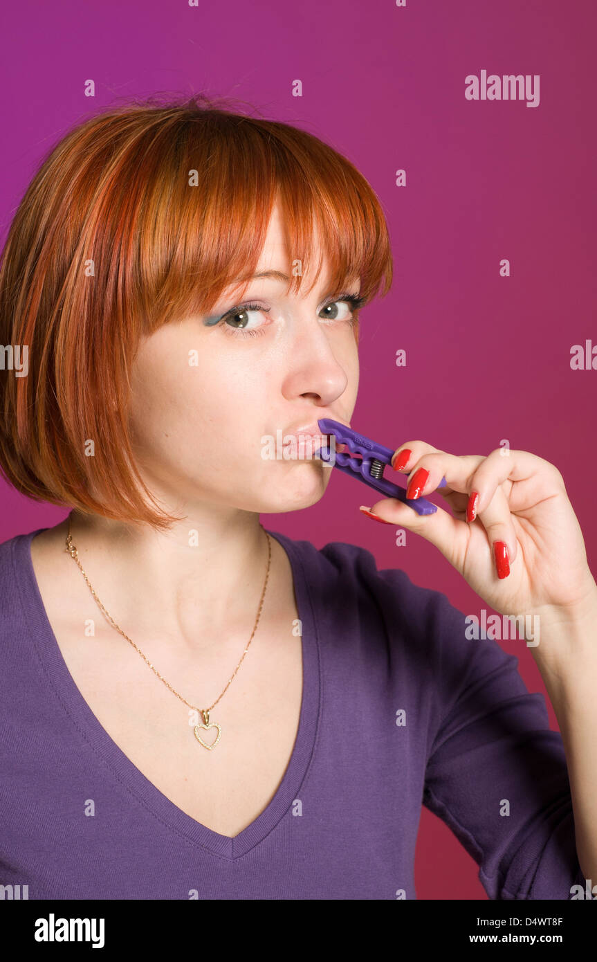 Portrait of beautiful red woman with clothespin posing at the studio ...